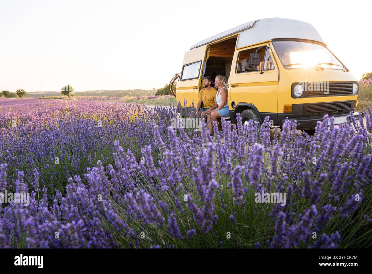 Young happy couple enjoying the view in their retro yellow camper van ...