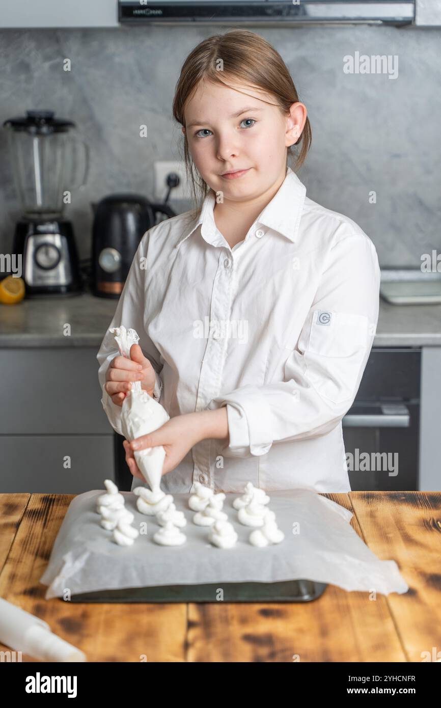 Cute little pastry chef girl in a white jacket holding a piping bag in ...