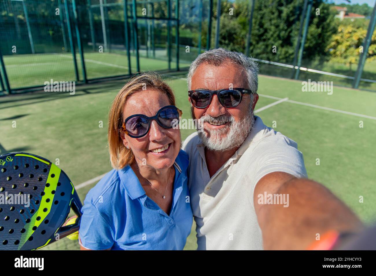 senior padel couple, both wearing sunglasses, celebrates their victory ...