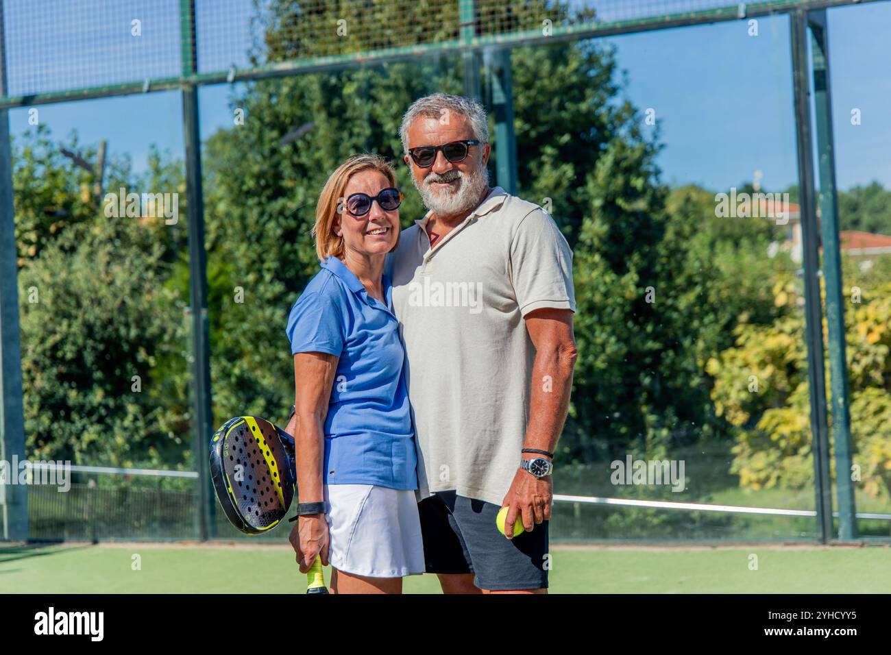 senior padel couple wearing sunglasses poses closely on the court ...