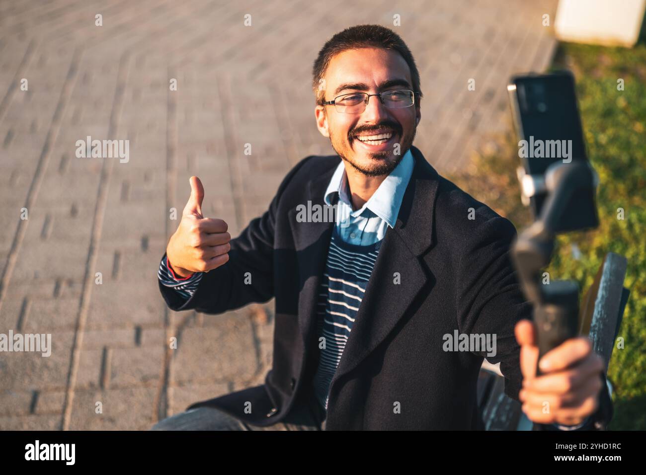 Businessman vlogger wearing eyeglasses and showing thumb up while using ...