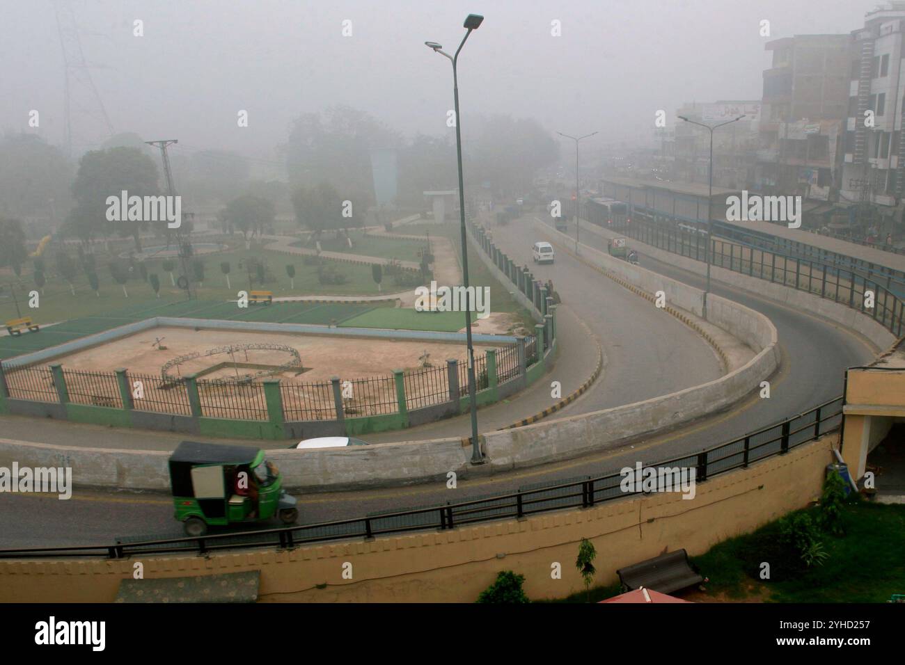 An auto rickshaw drives on a road as smog envelops the area of Peshawar ...