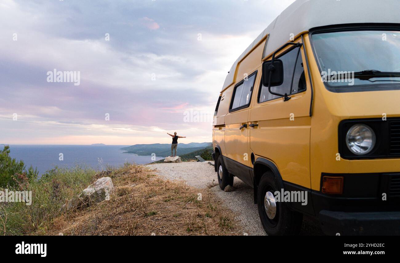 Yellow retro camper van parked on a dirt road above the sea on Korcula ...