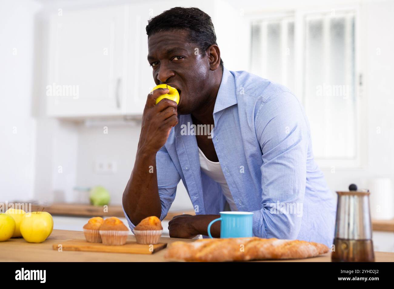 Man eating apple in kitchen at home Stock Photo - Alamy