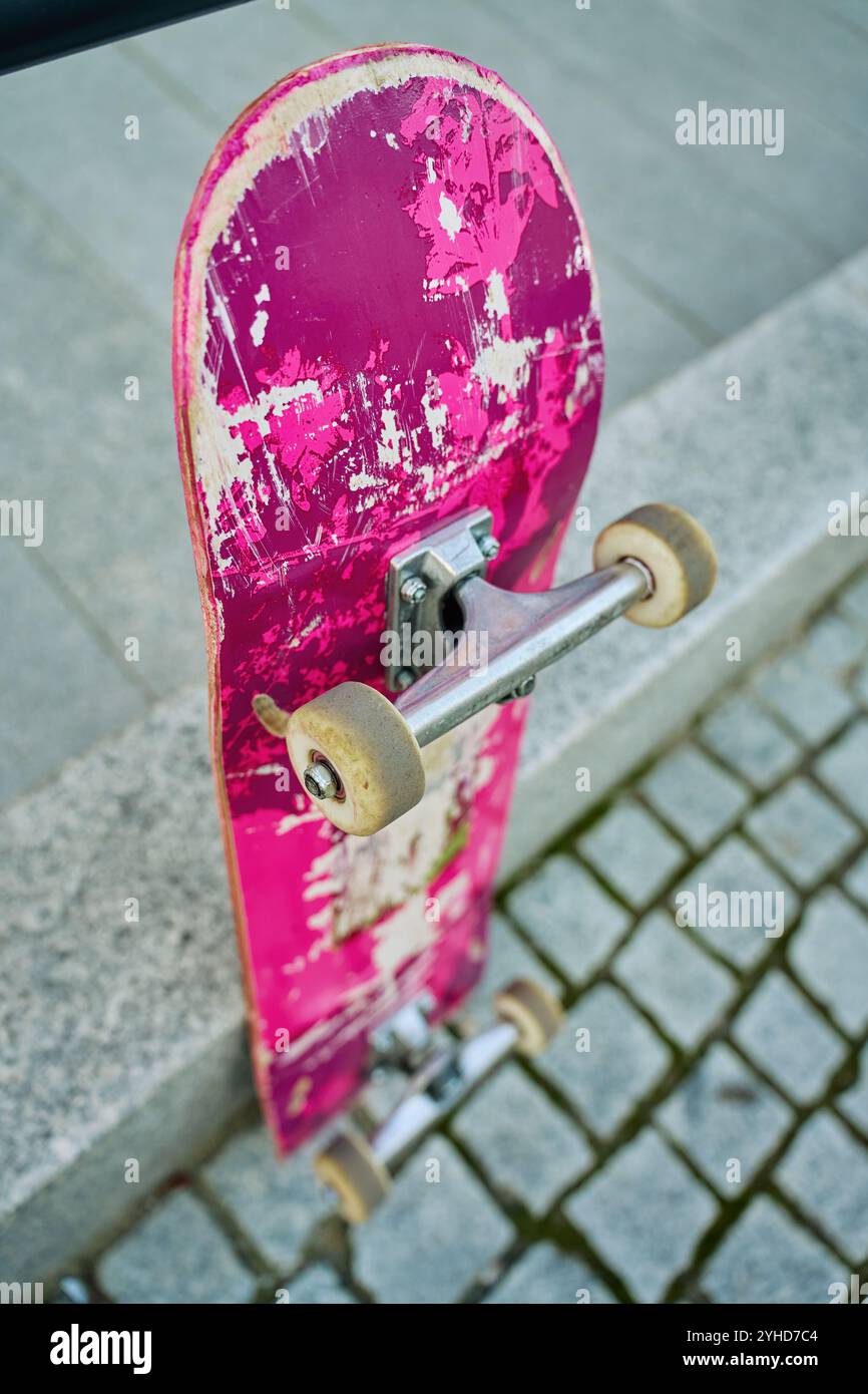 Used scratched pink skateboard against stone wall at city street. Urban ...