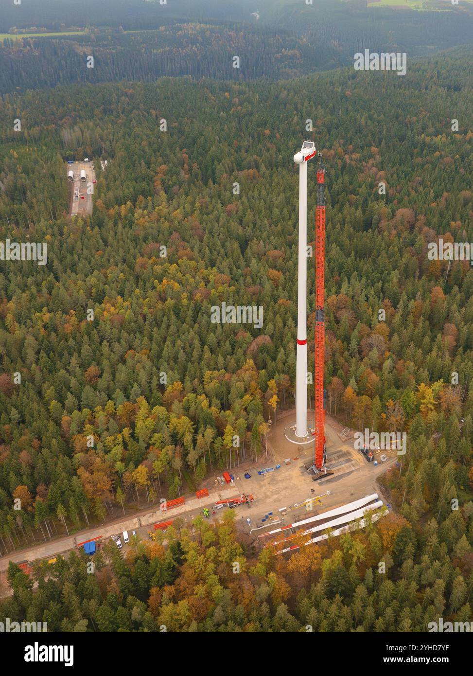 A wind turbine is erected with the help of a crane in the dense autumn ...