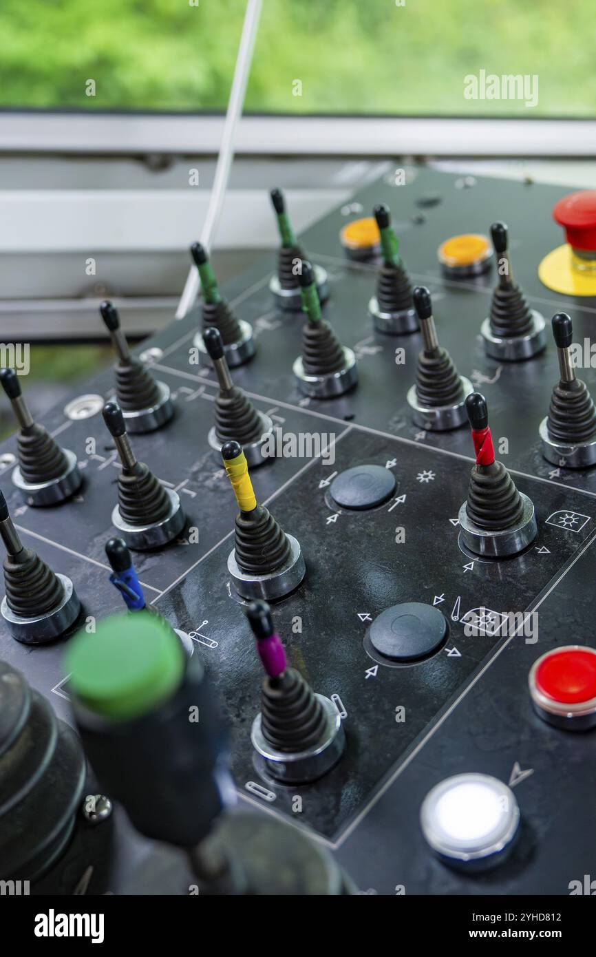 Control panel with levers and coloured buttons in front of a window ...