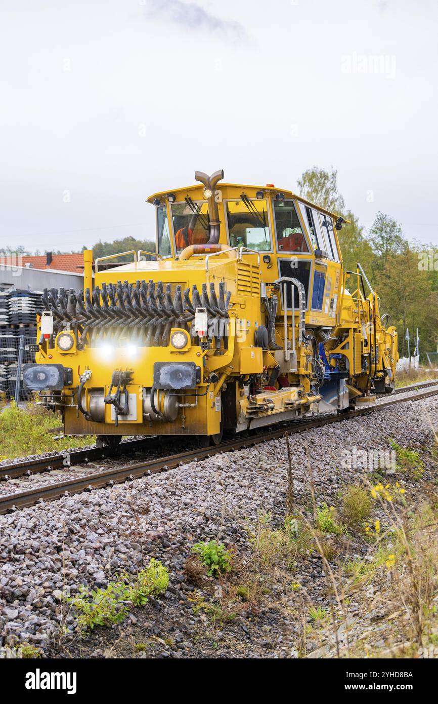 Yellow railway vehicle on tracks in an environment with industrial ...