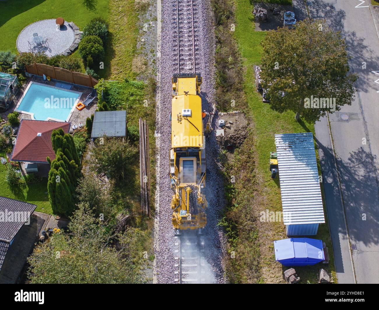 Yellow train runs on rails through a village, surrounded by houses and ...