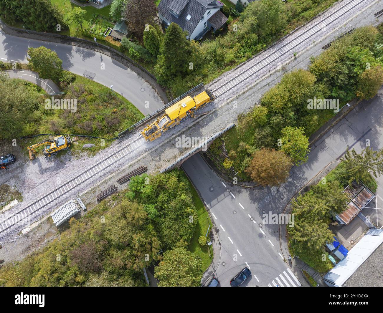 A yellow construction machine on railway tracks crosses a bridge on a ...