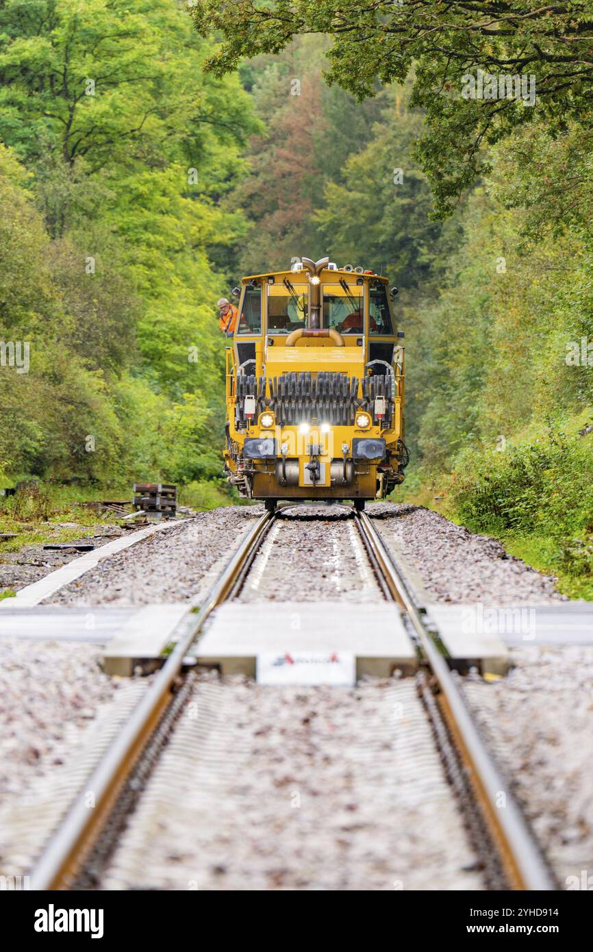 The yellow tractor unit approaches on a railway track, flanked by green ...
