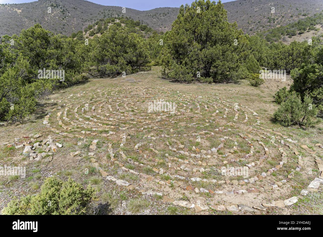 A labyrinth lined with stones in a clearing in a mountain forest ...
