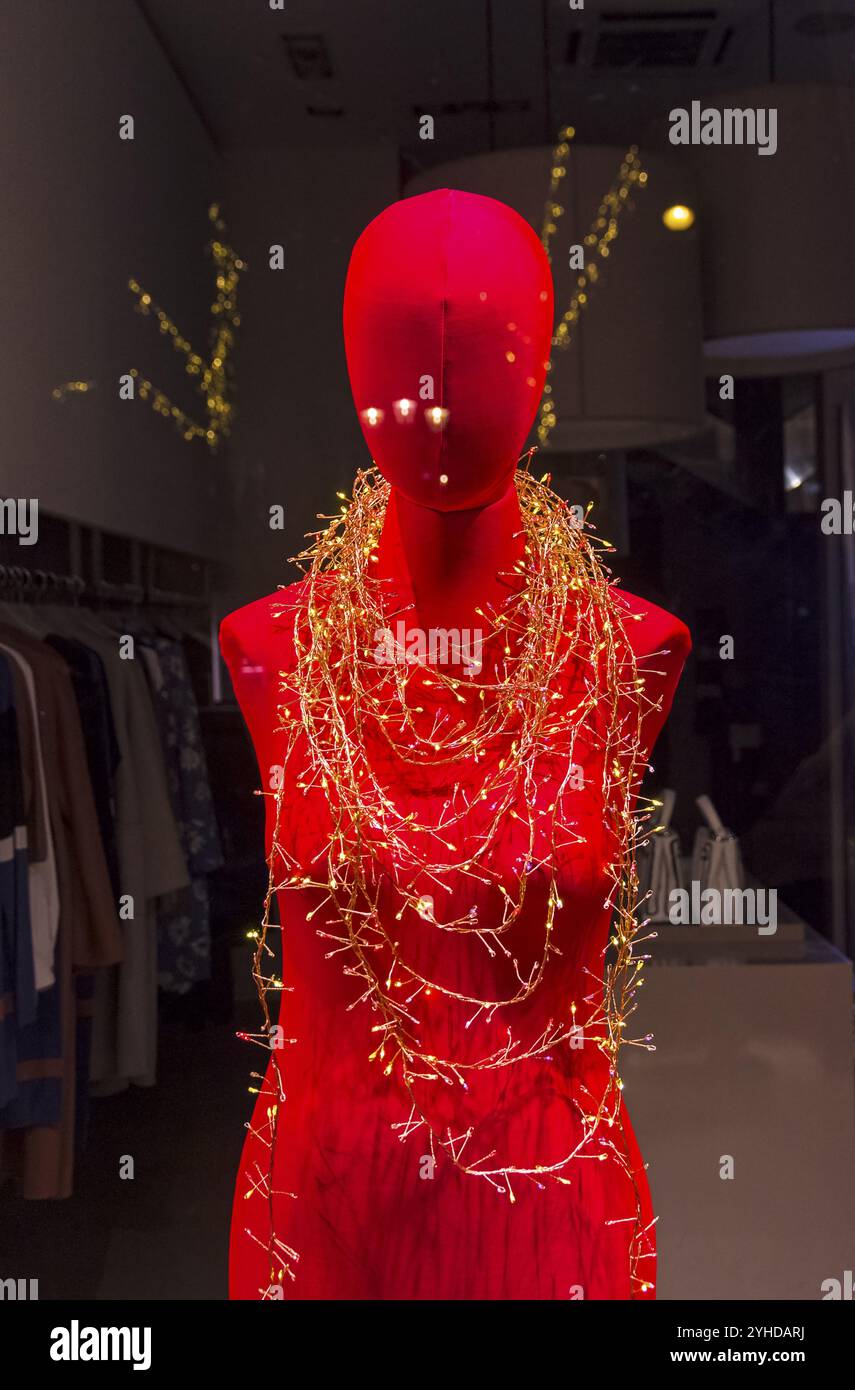 Showcase of an expensive clothing store. Red mannequin with a garland ...