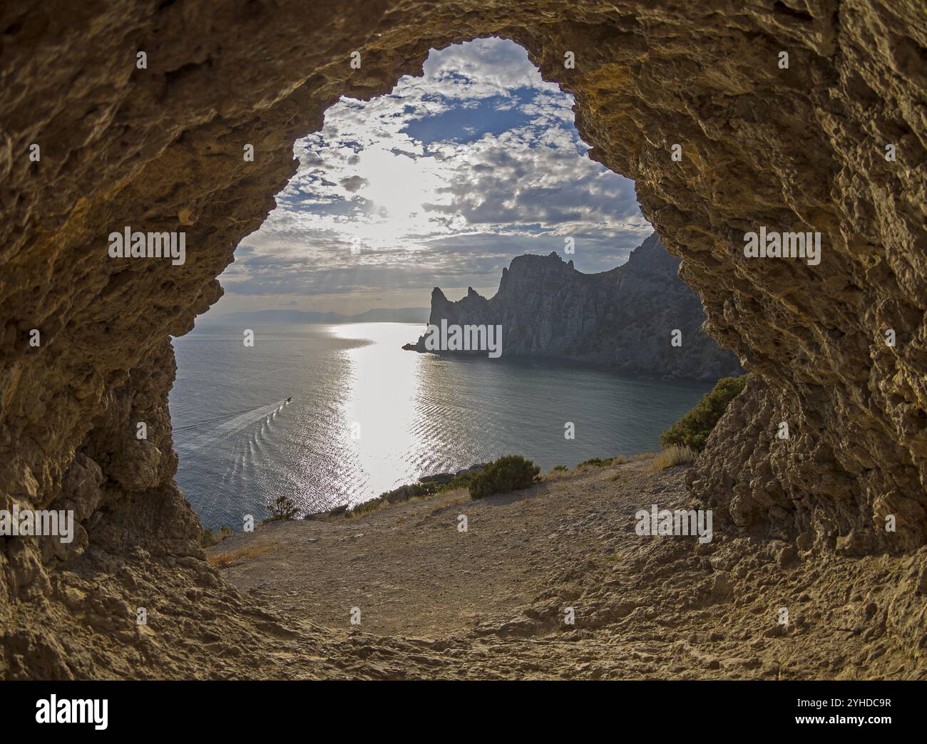 View of the sunny lane and the coastal cliffs from a small rocky grotto ...