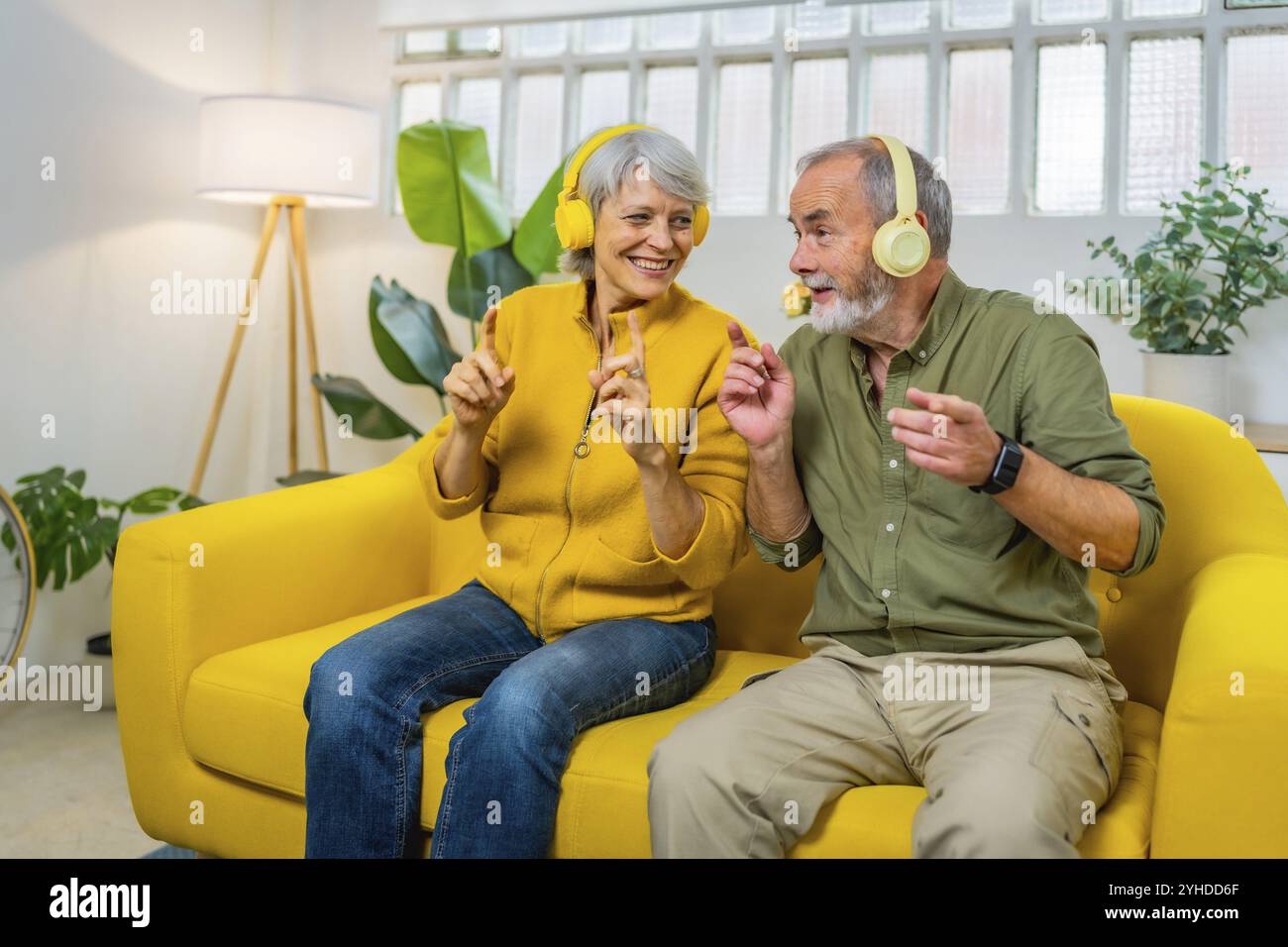 Cute senior couple listening to music together and dancing sitting on ...
