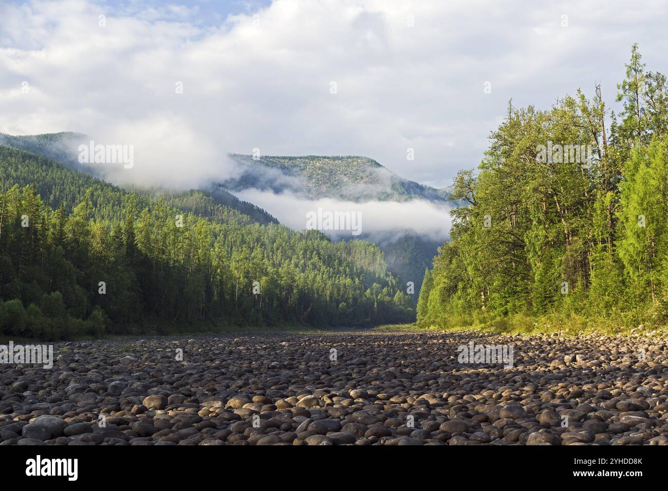 Low clouds on a mountainside. Dry river bed of the Oka Sayanskaya River ...