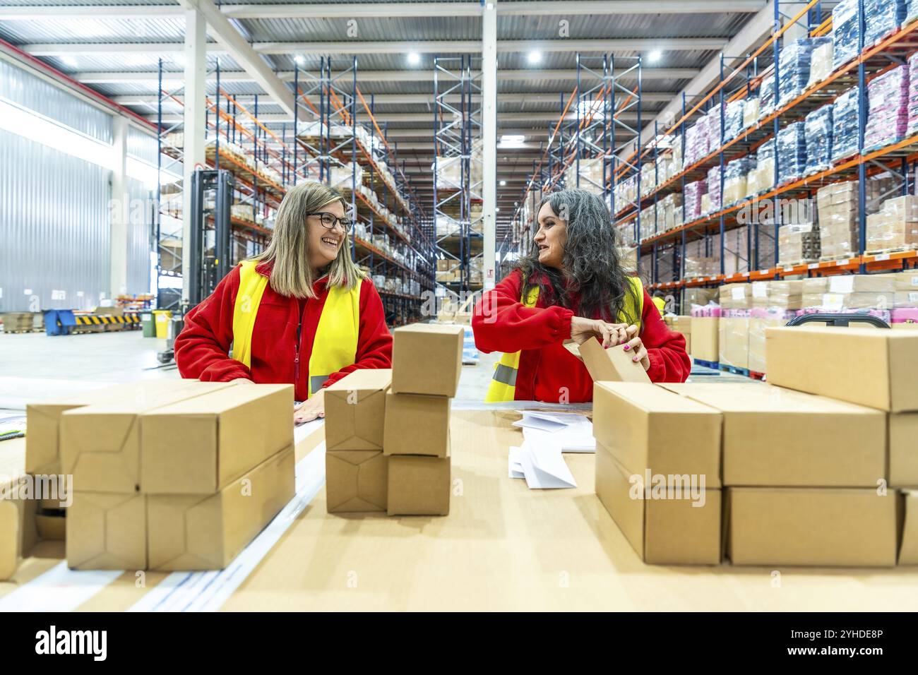 Happy female caucasian manual workers organizing boxes to ship in a ...