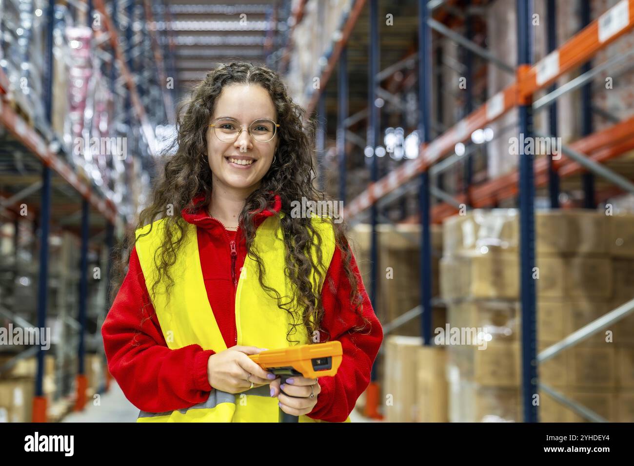 Frontal portrait of a happy young female employee holding a scanner in ...