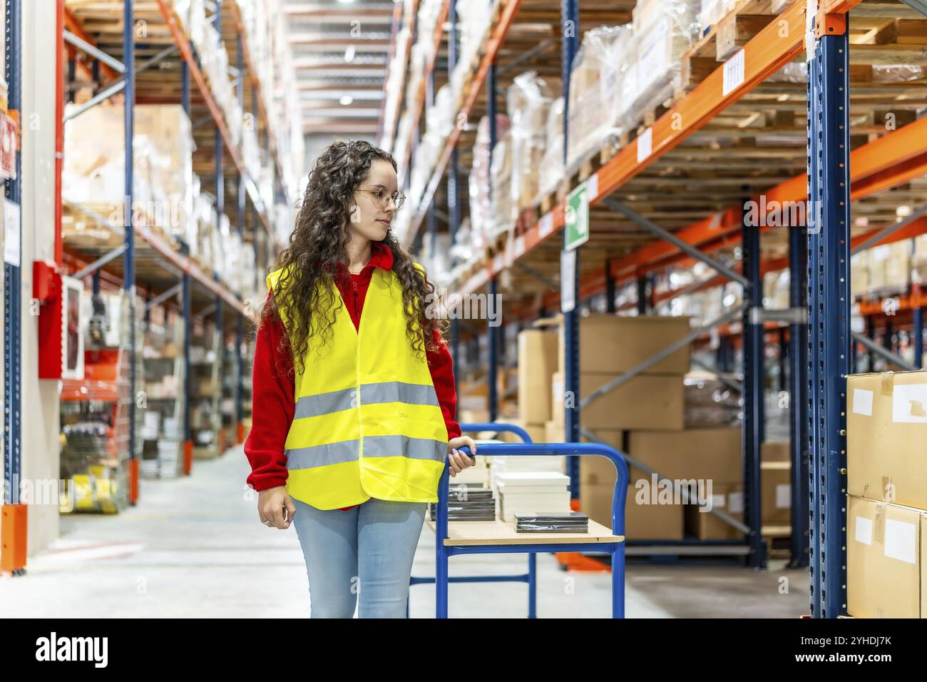 Woman worker in safety clothes walking pushing boxes in a cart at ...