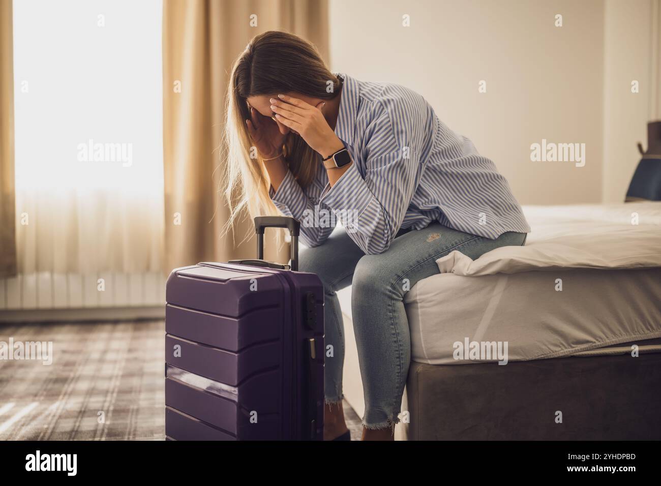Tourist arrived in hotel room with her suitcase. She is tired of travel ...