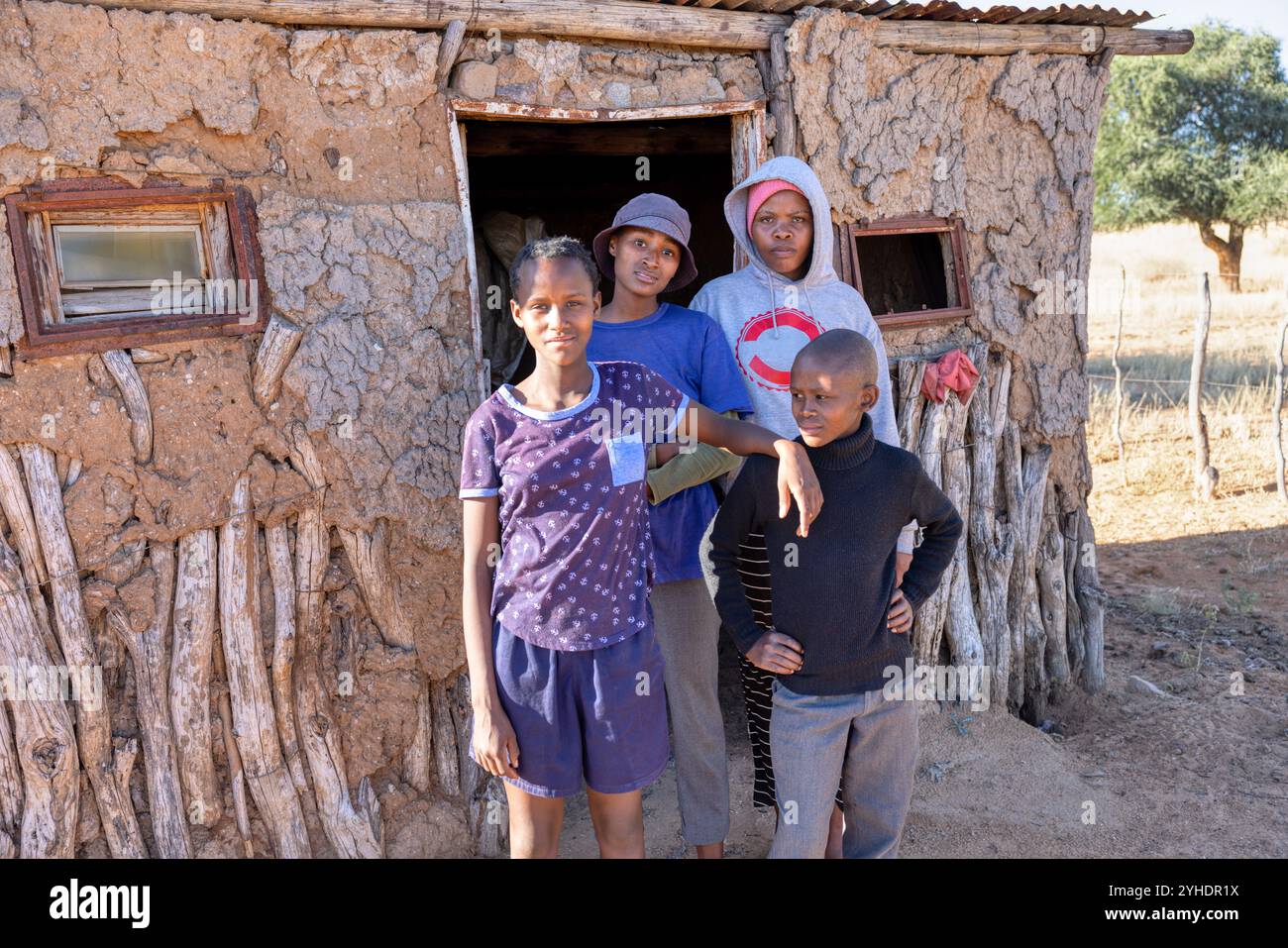 african village, happy family kids , standing in front of the mud shack ...