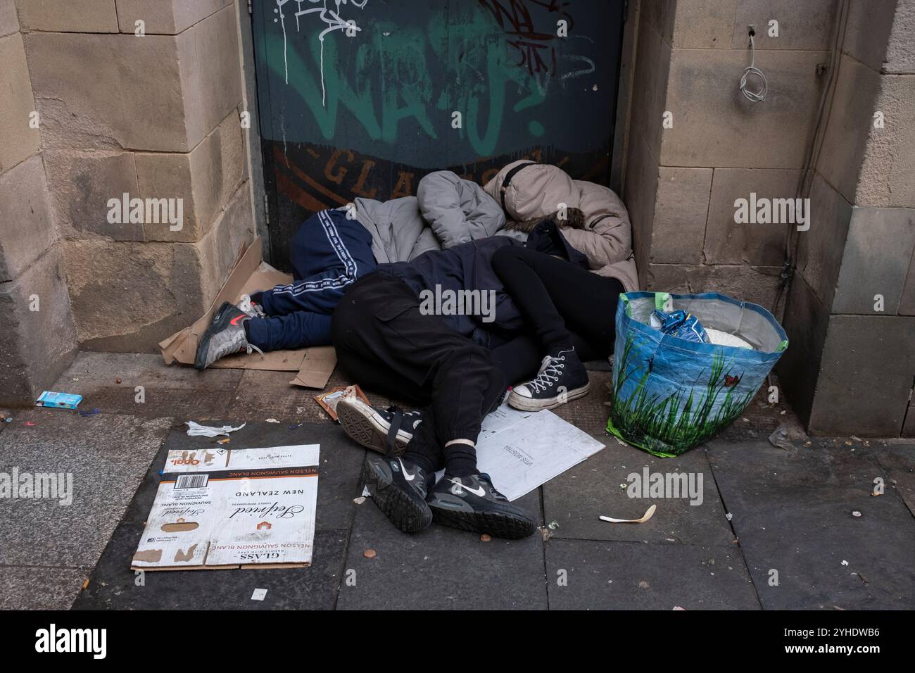 Three homeless people sleeping in a doorway in the city centre, in ...