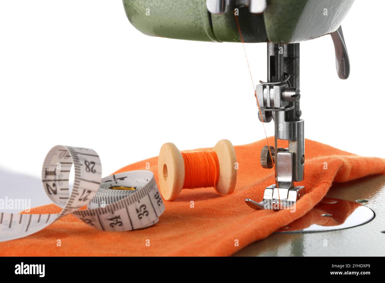 Sewing machine with orange fabric, measuring tape and spool of thread ...