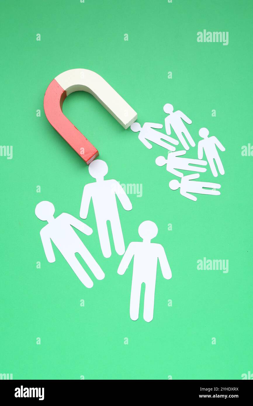 Magnet attracting paper human figures on green background, flat lay ...