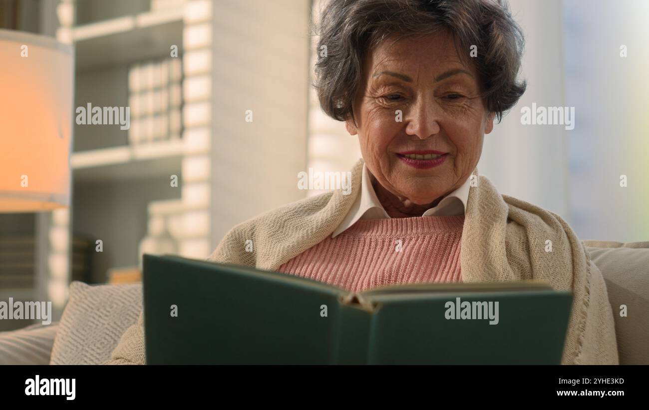 Happy inspired Caucasian old woman reading book smiling nostalgic ...