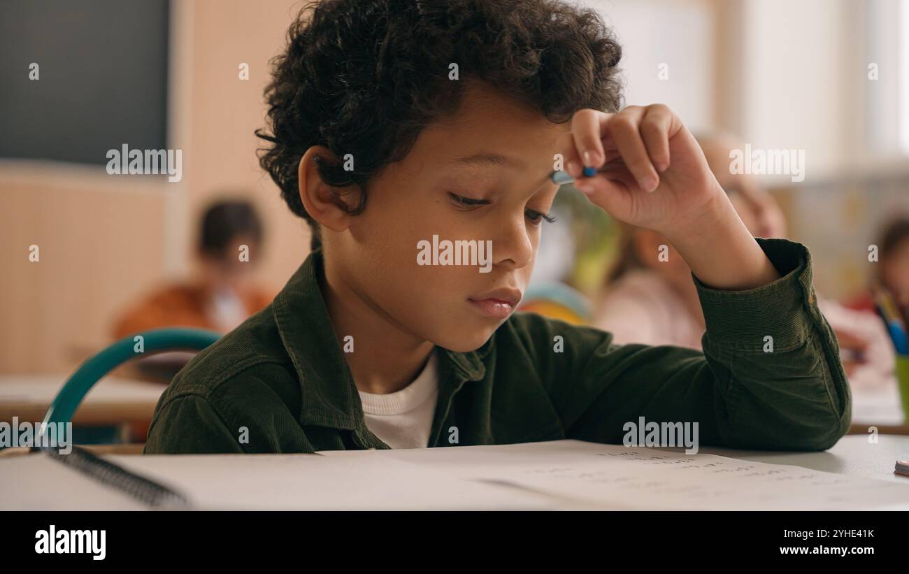 Little African American guy boy writing notes task class lesson primary ...