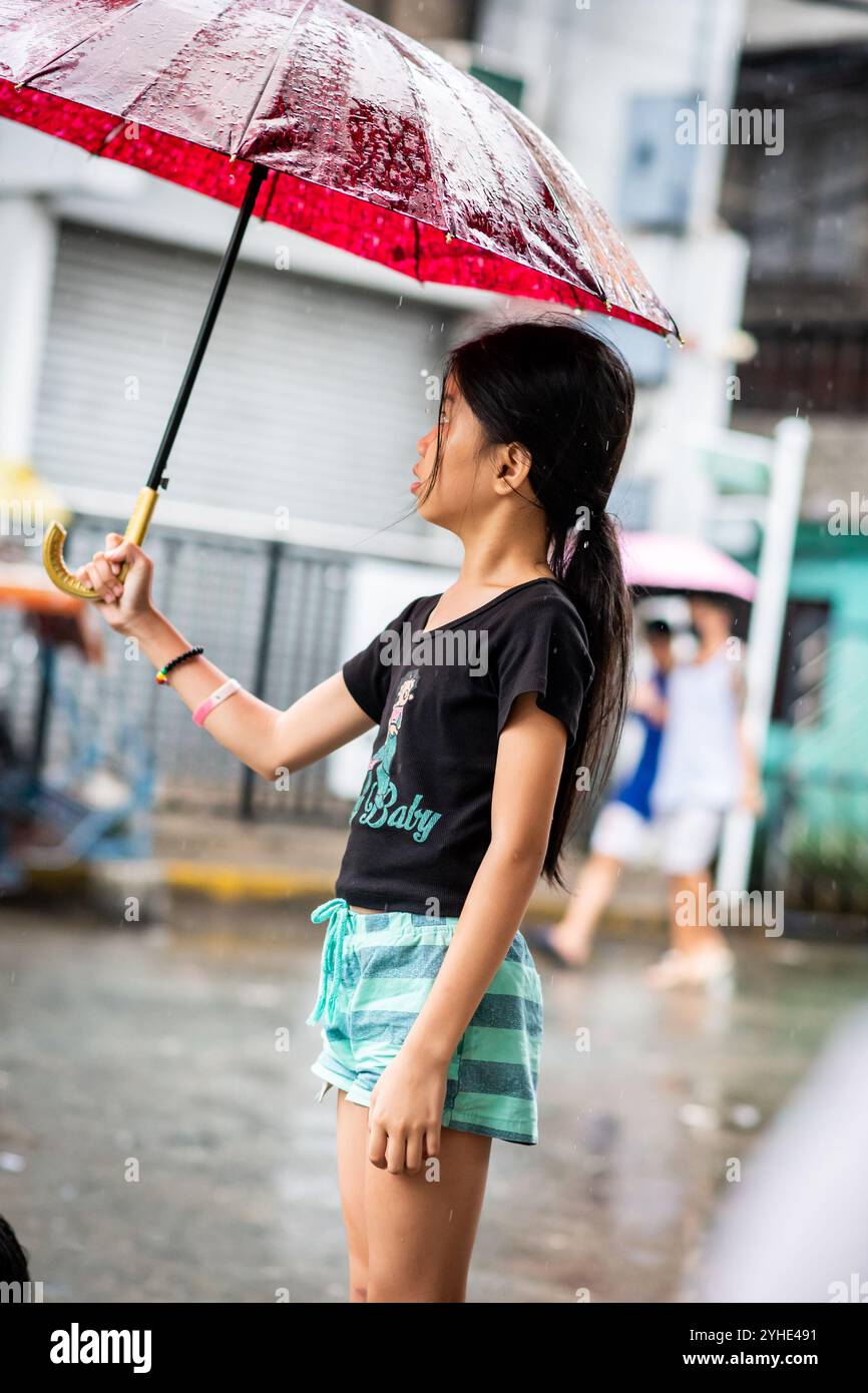 A young Filipino carries her umbrella through the rain in the Binondo ...