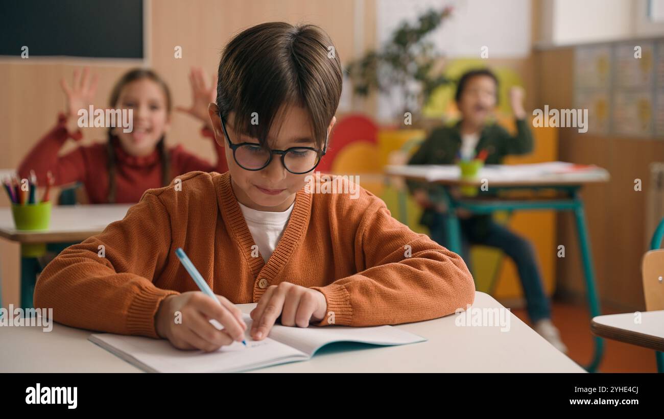 Caucasian little boy kid schoolboy nerd in glasses write task class ...