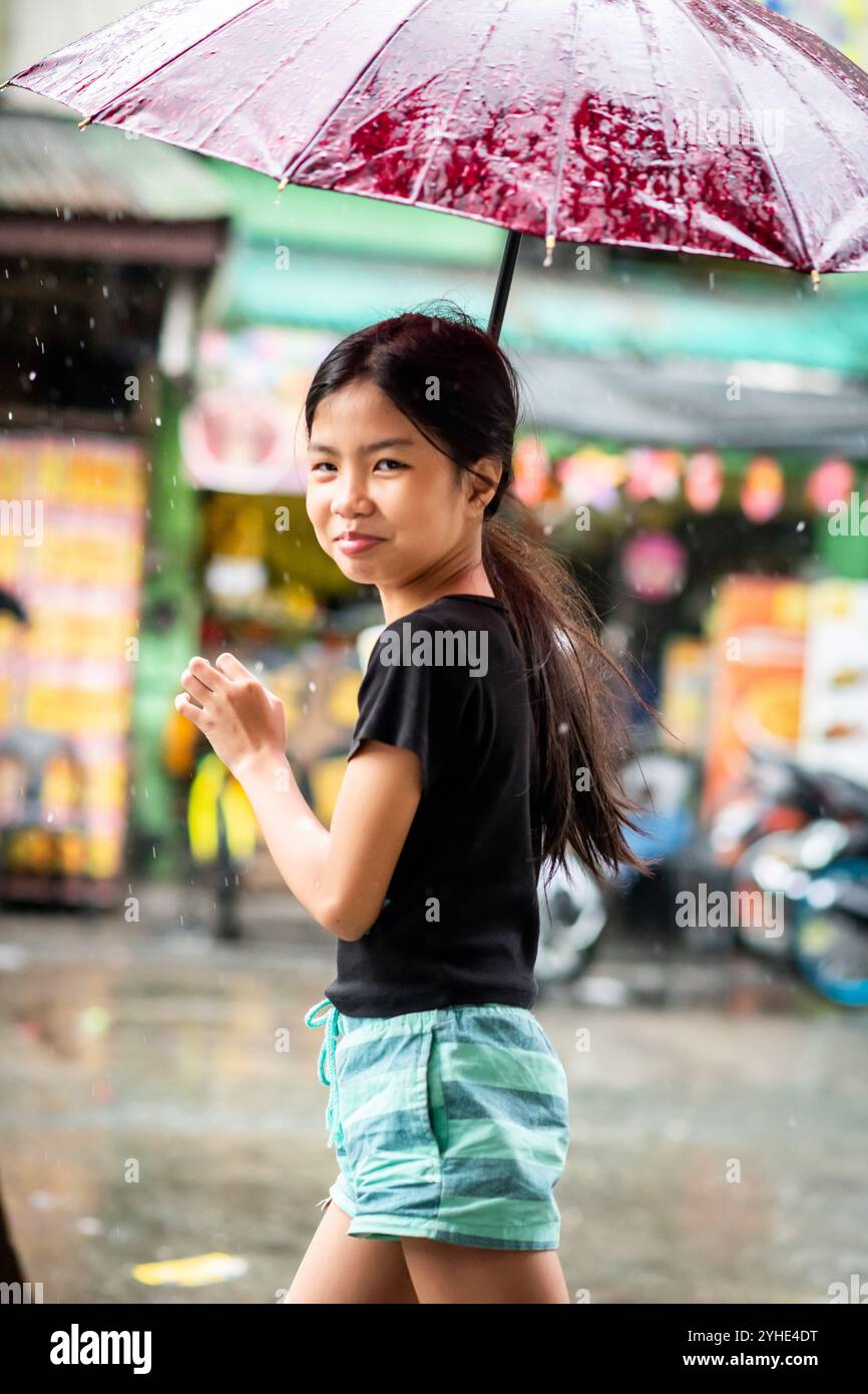 A young Filipino carries her umbrella through the rain in the Binondo ...
