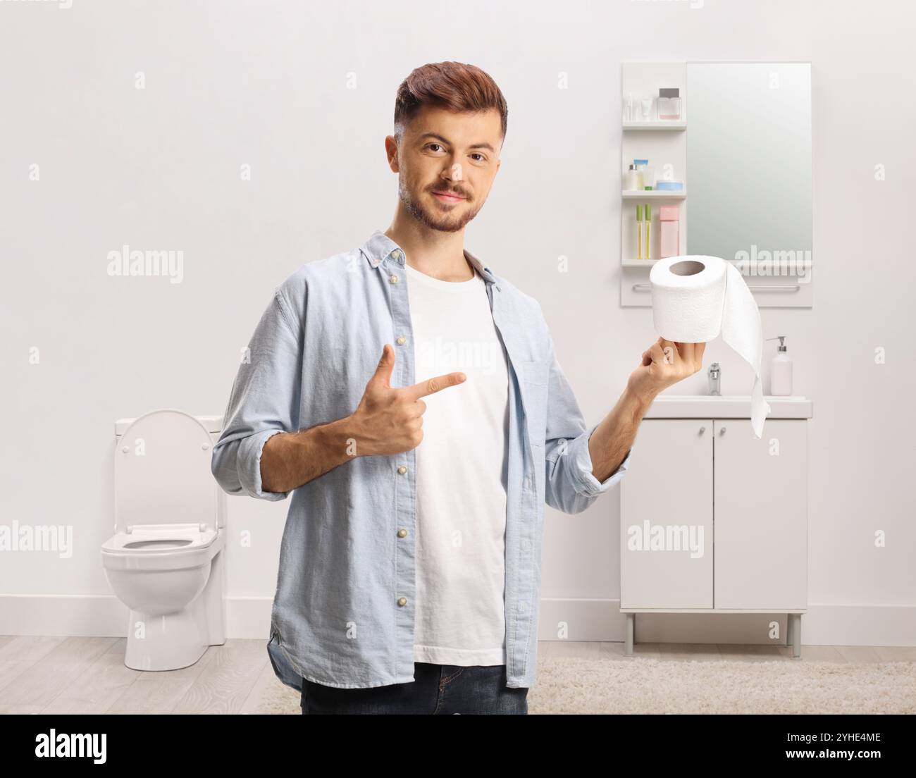 Guy pointing at a toilet paper roll in a bathroom Stock Photo - Alamy