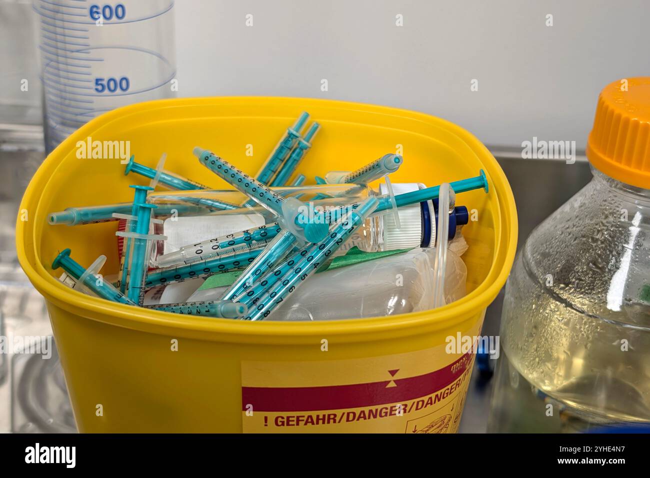 a yellow waste box labeled danger filled with used syringes in a ...