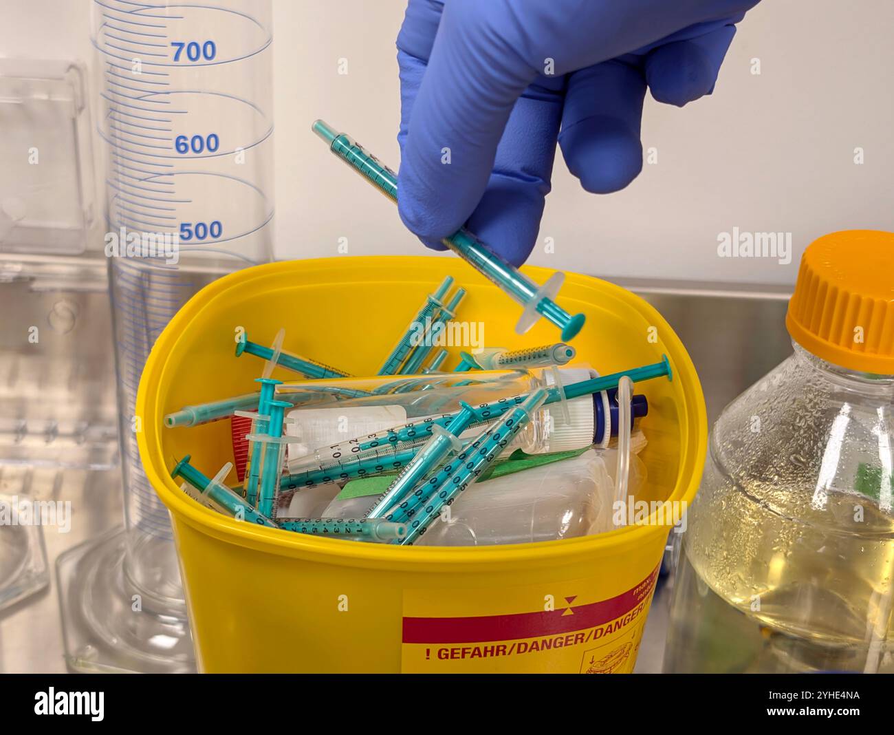 a yellow waste box labeled danger filled with used syringes in a ...