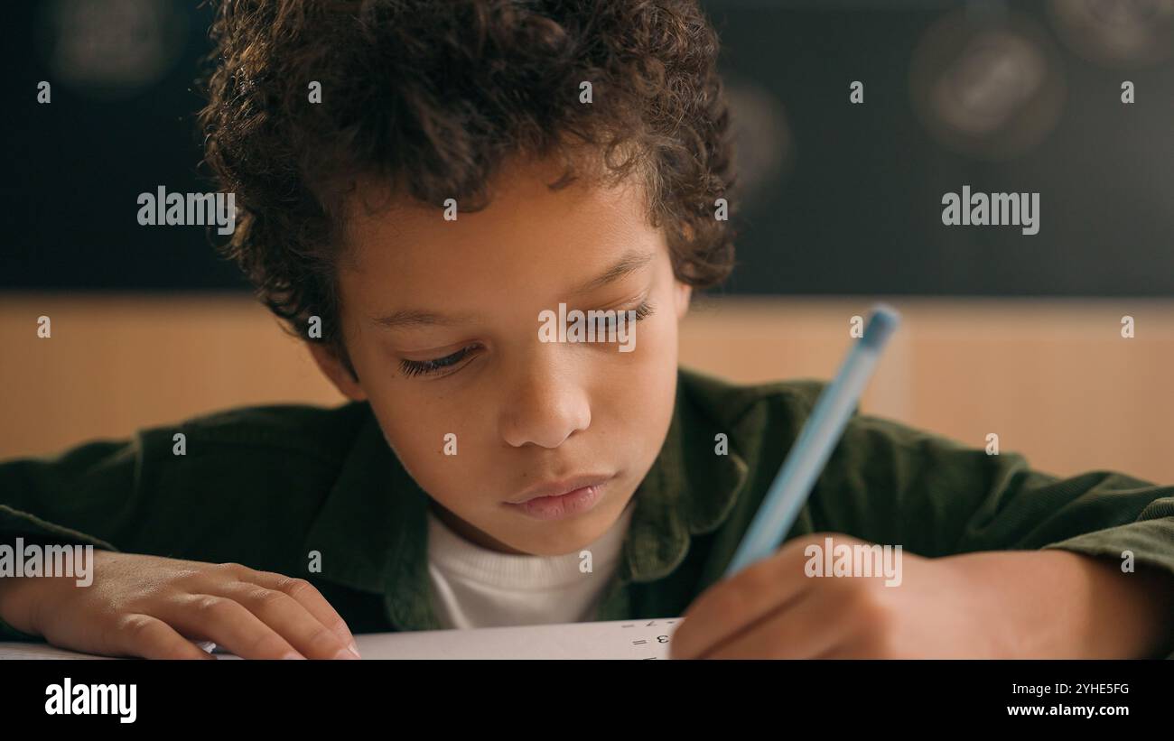 Little African American guy boy writing notes task class lesson primary ...