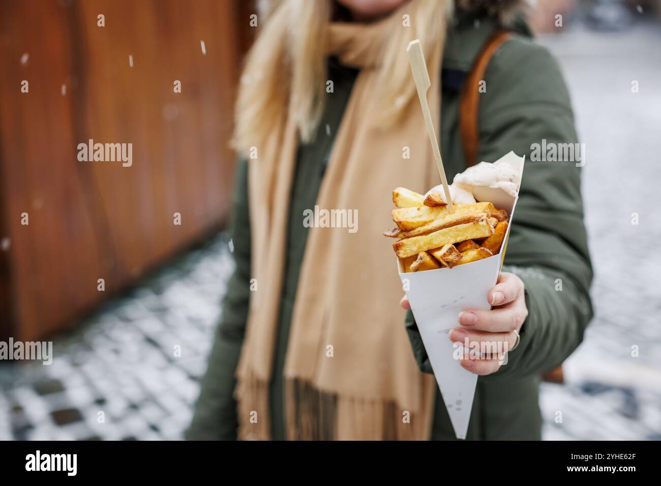 Woman holding french fries at city street in winter. Refreshment from ...