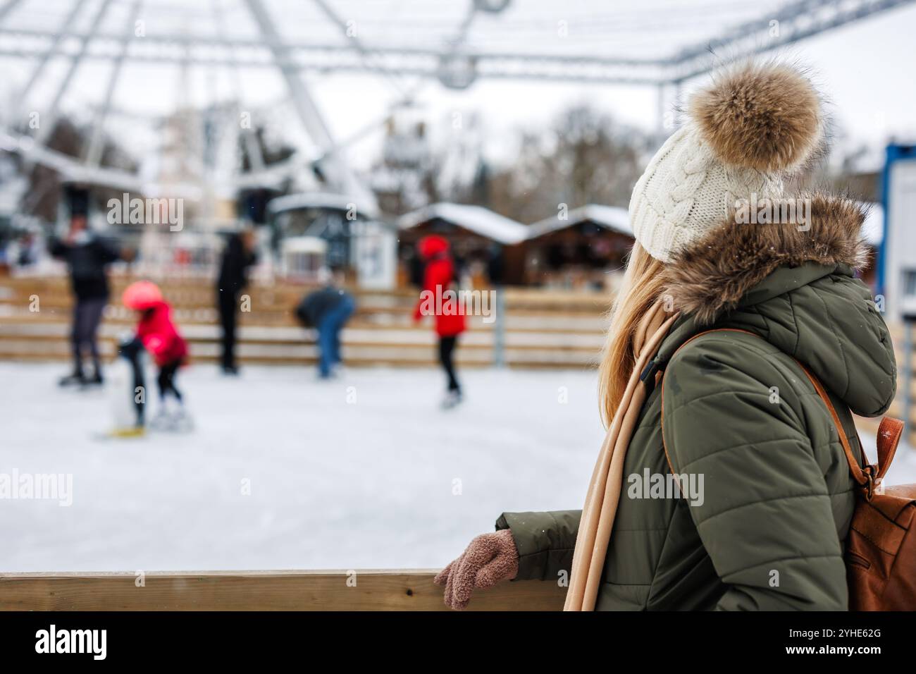Woman is looking at crowd of people ice skating on rink. Christmas ...