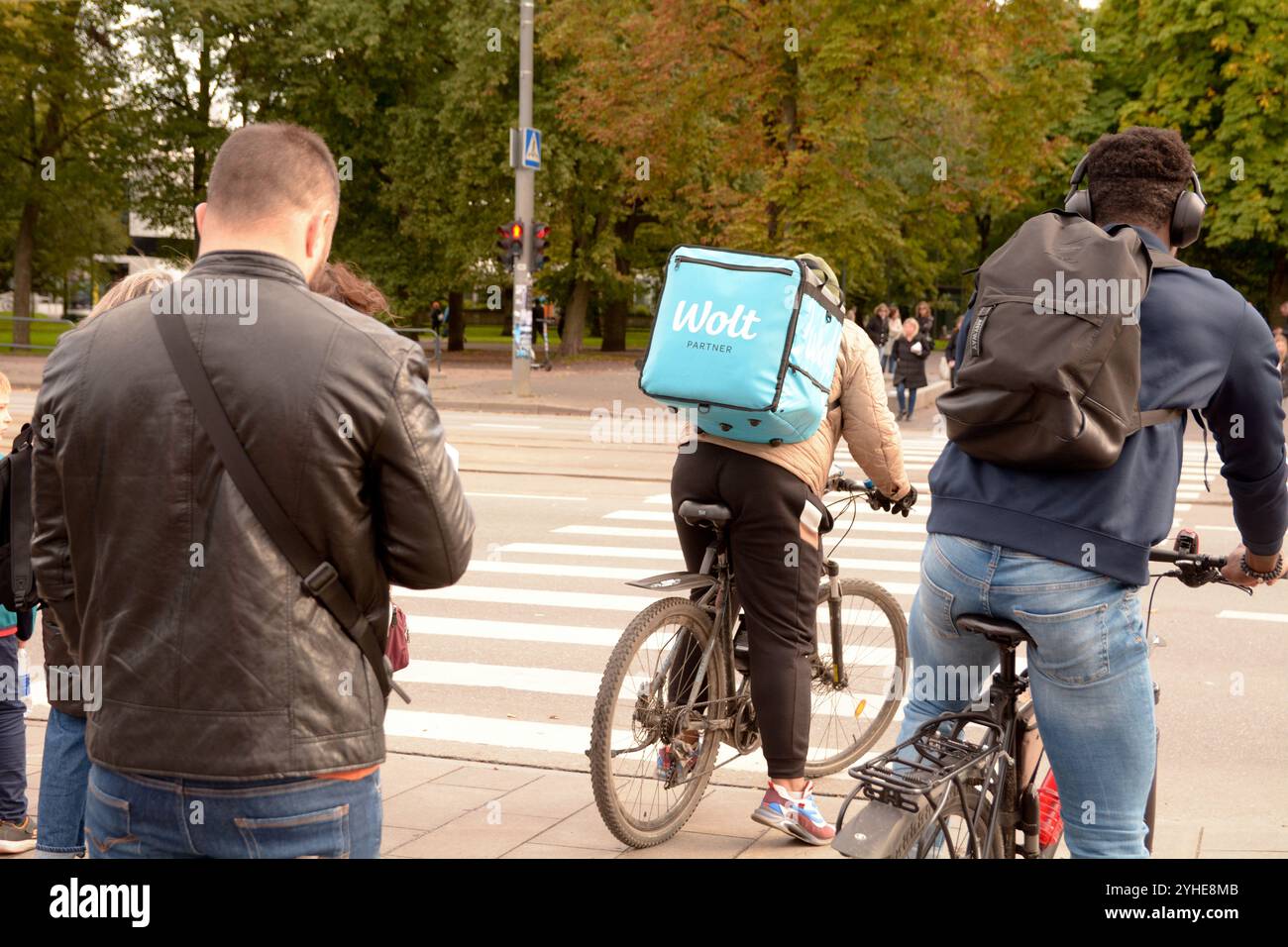 Wolt food delivery rider on a bicycle waiting at a pedestrian crossing ...