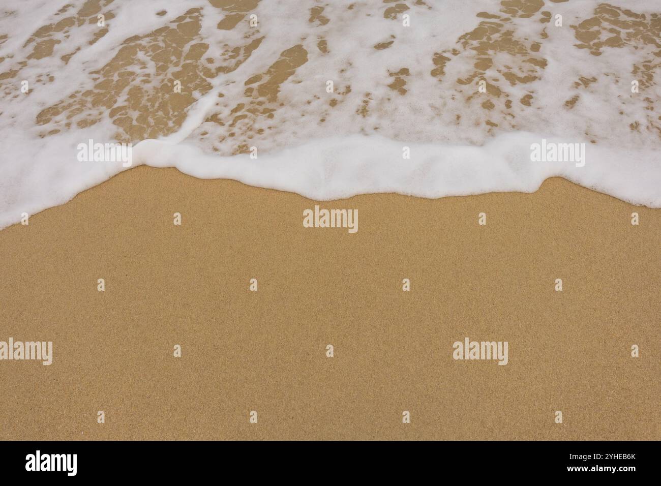 Background close-up of ocean waves rolling on the sand on the beach ...