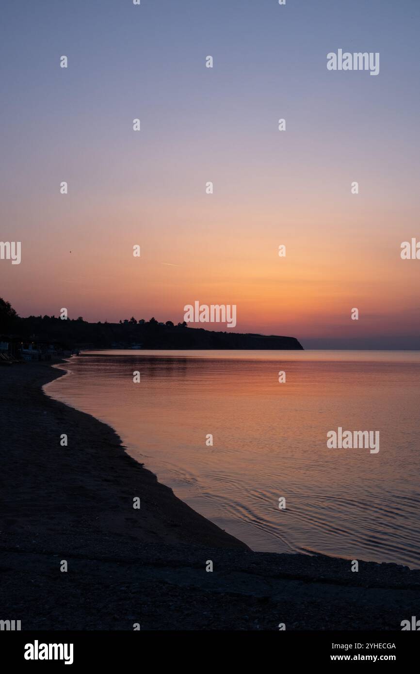 Beautiful orange-pink early summer sunset over the sea in Greek shore ...
