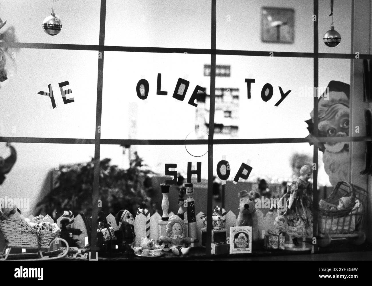 A sly Santa peeks around the front window of a toy store, ca. 1945 ...