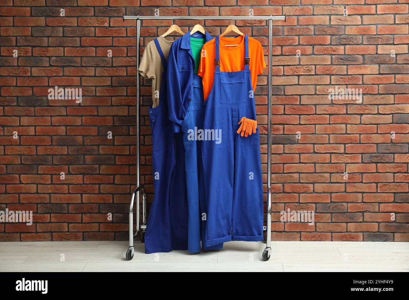 Different workers' uniforms on clothing rack near brick wall Stock ...
