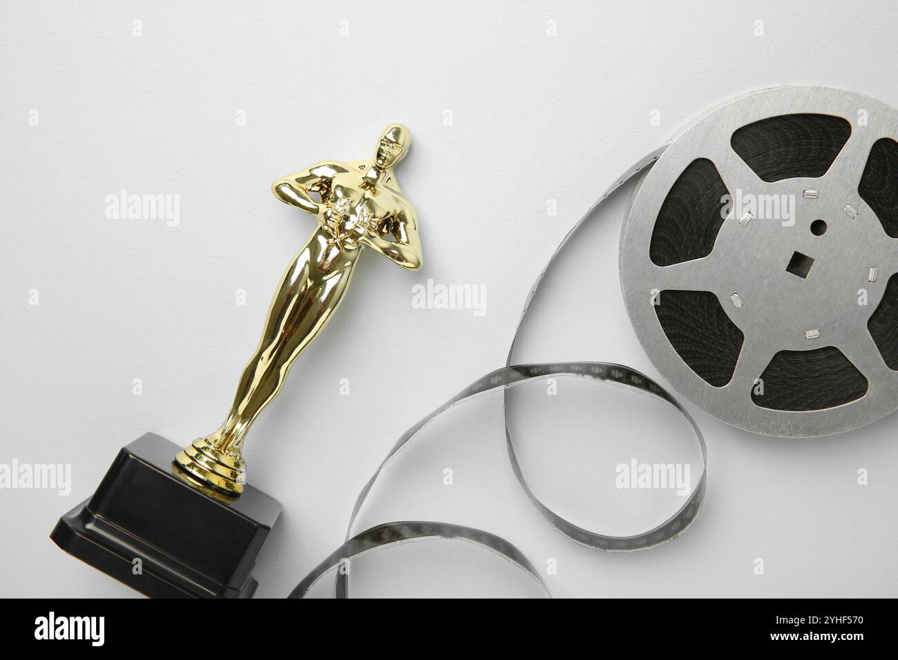 Golden trophy in shape of human figure and film reel on white ...
