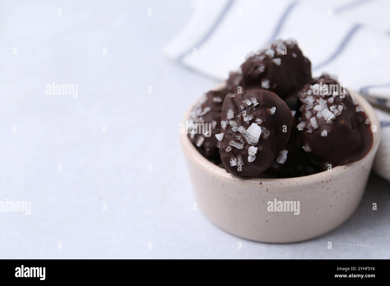 Tasty chocolate candies with salt in bowl on light table, closeup ...
