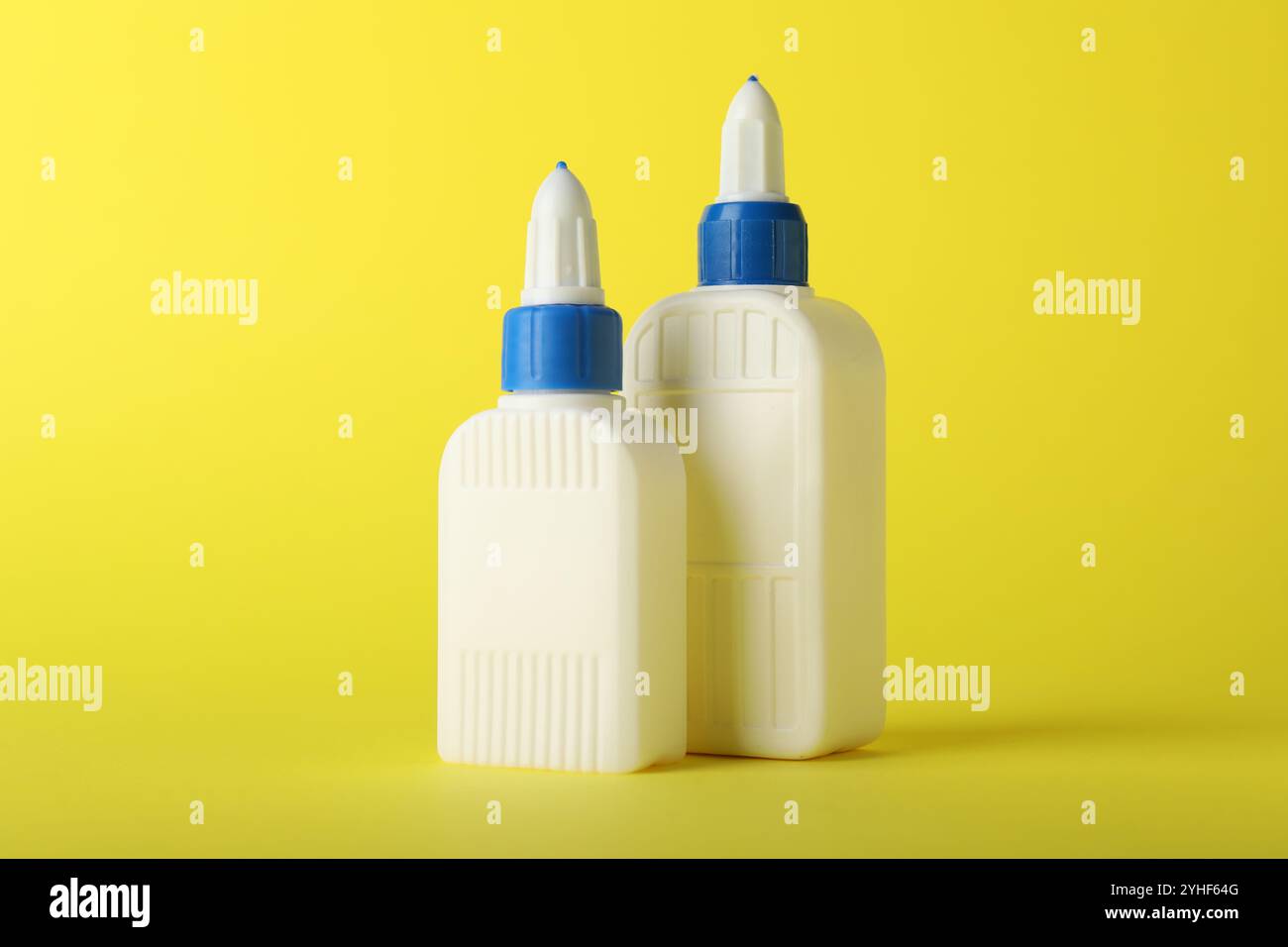 Two bottles of glue on yellow background Stock Photo - Alamy