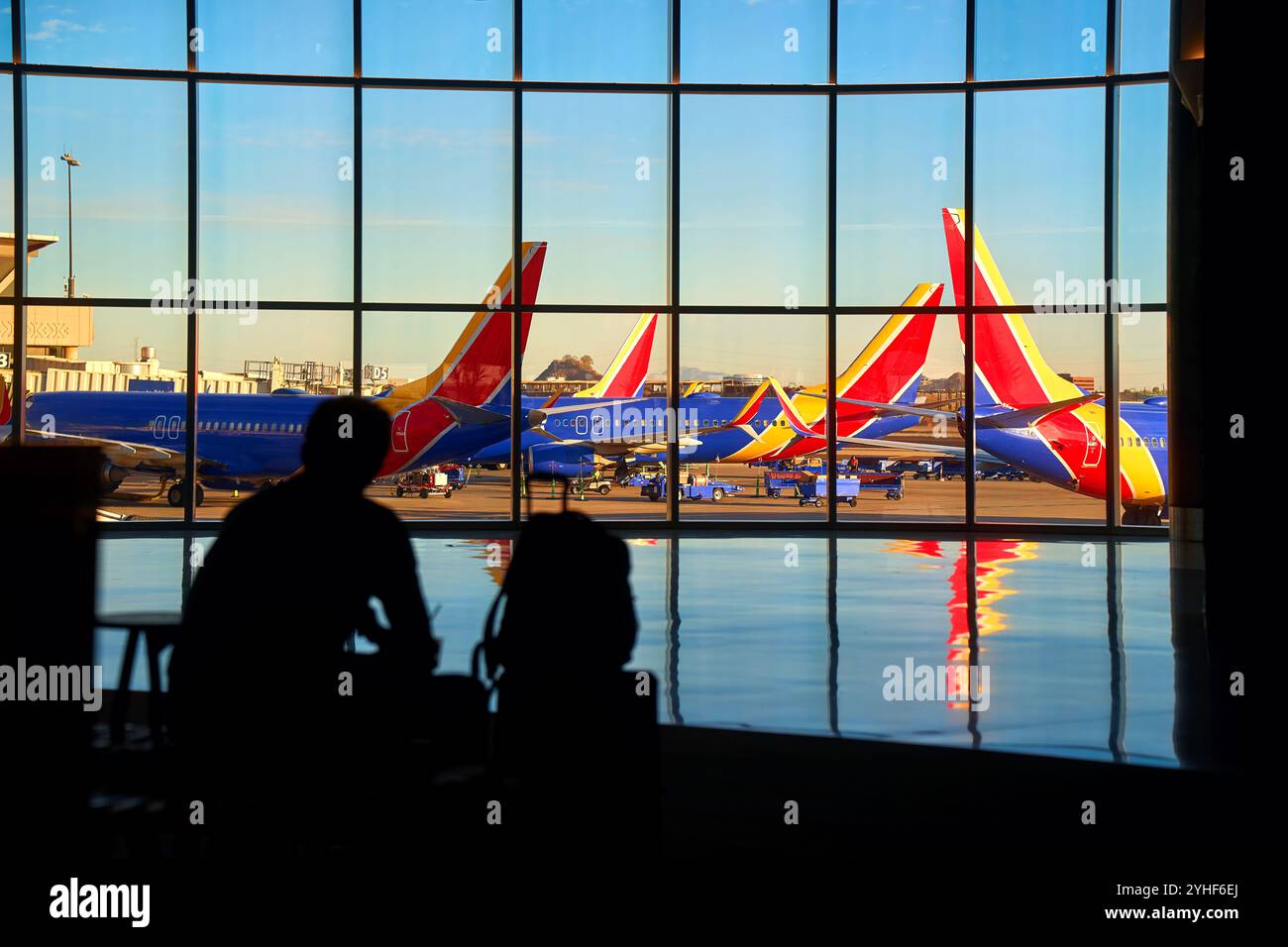 a passenger at the airport stands at a window with a view of the planes ...