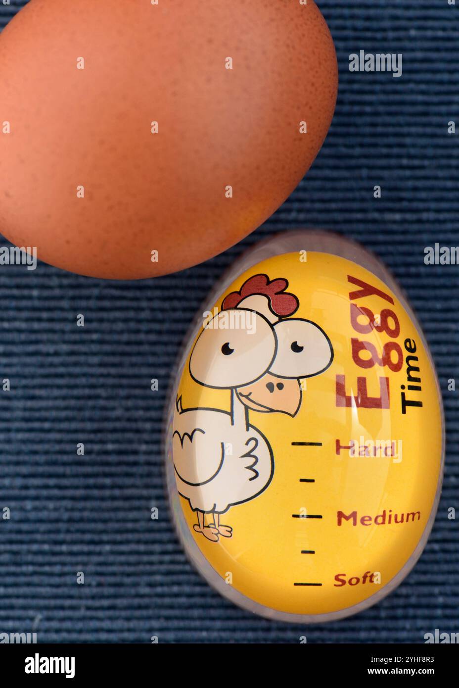 Yellow egg timer kitchen gadget and egg Stock Photo - Alamy