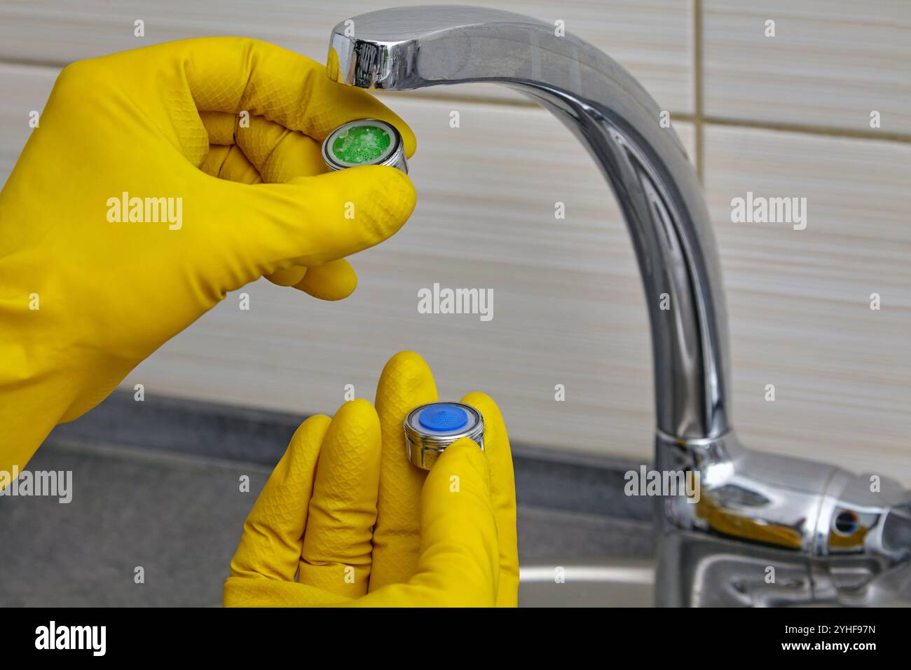 replacing a clogged faucet aerator with a new one. plumber in yellow ...